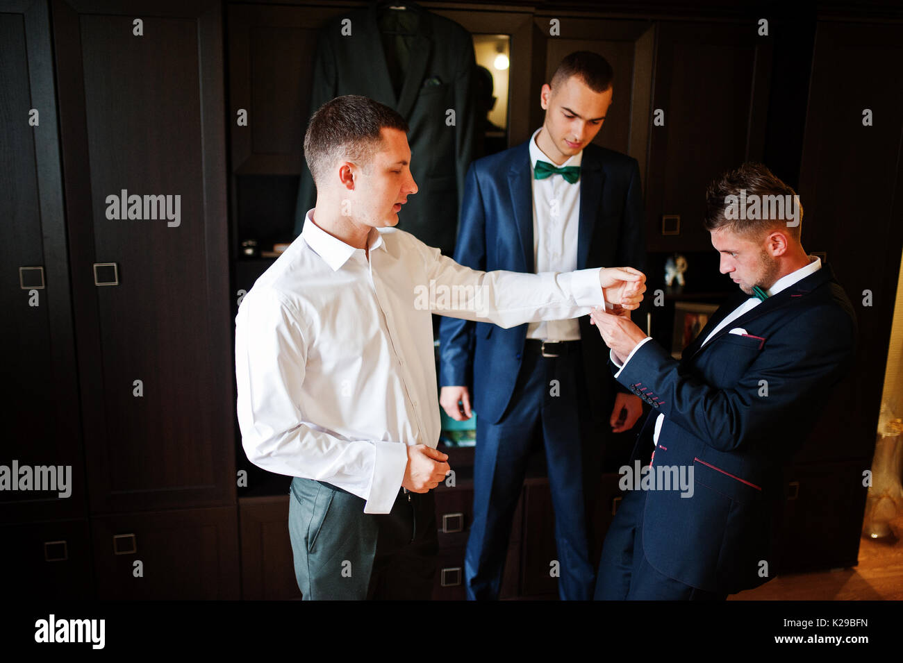 Groomsmen helping groom to dress up and get ready for his wedding ...