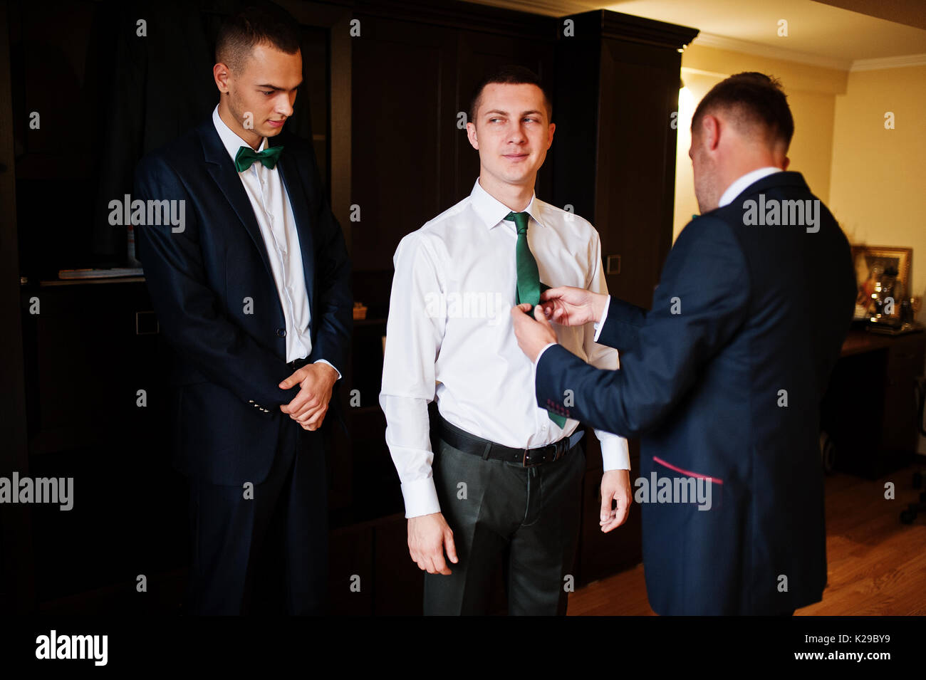 Groomsmen helping groom to dress up and get ready for his wedding ...