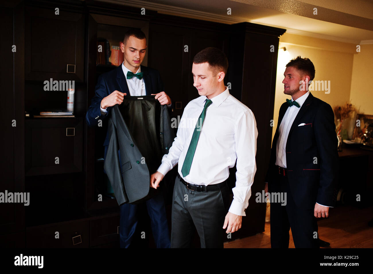 Groomsmen helping groom to dress up and get ready for his wedding ...