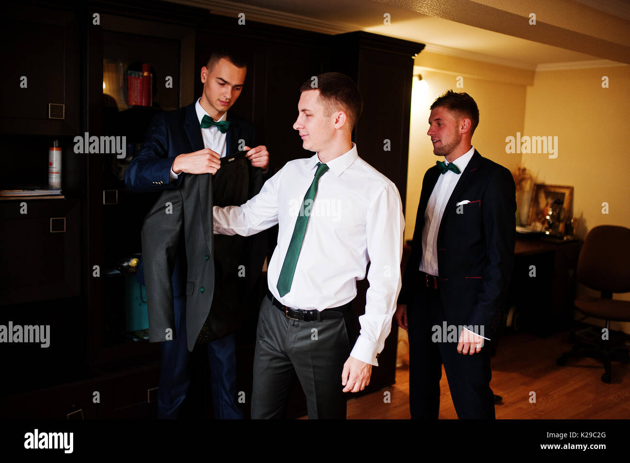 Groomsmen helping groom to dress up and get ready for his wedding ...