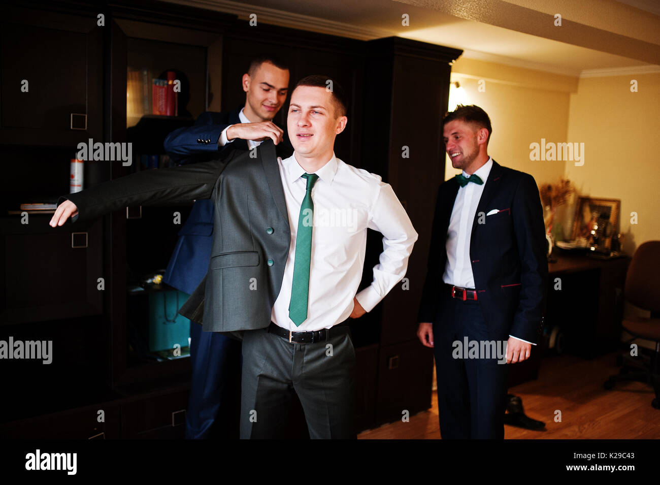Groomsmen helping groom to dress up and get ready for his wedding ...