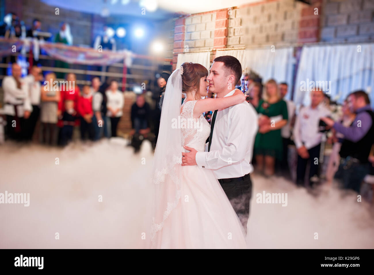 Wedding couple dancing their first wedding dance with heavy smoke and different lights in the ...