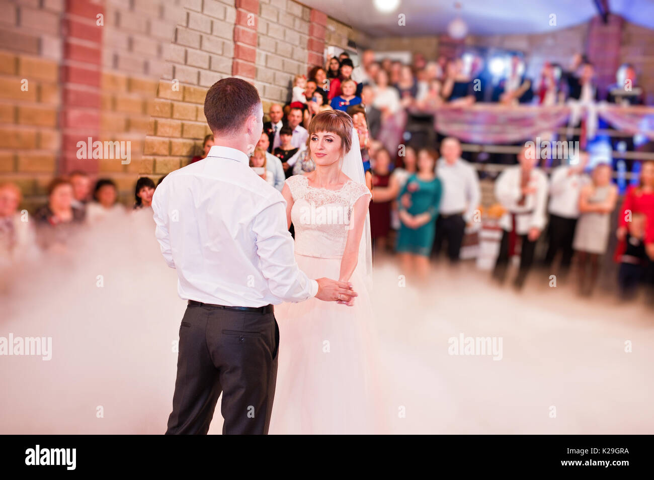 Wedding couple dancing their first wedding dance with heavy smoke and different lights in the ...