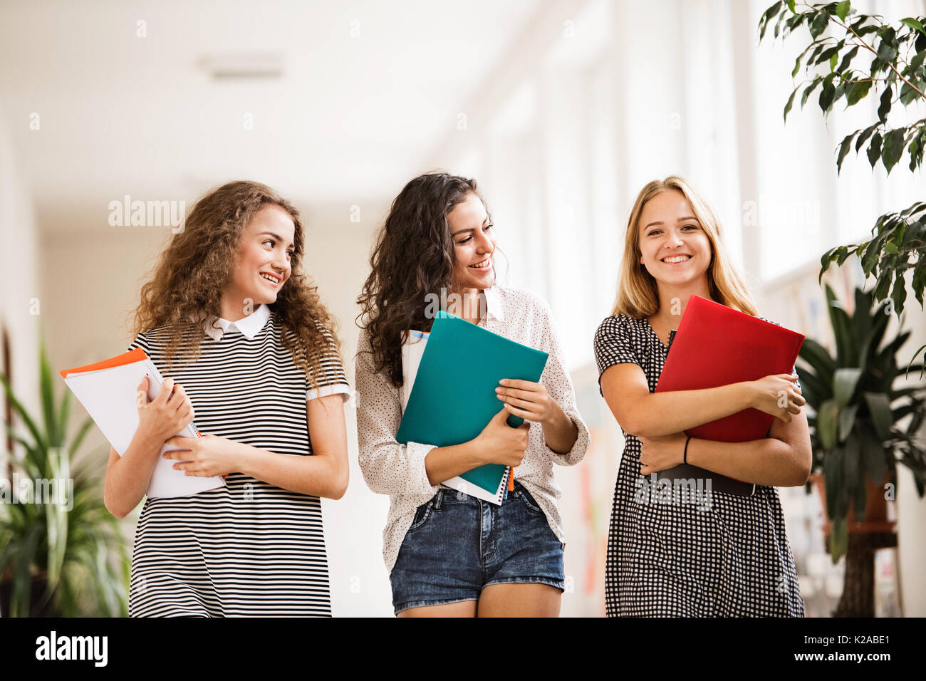 Three teenage girls in high school hall during break Stock Photo - Alamy