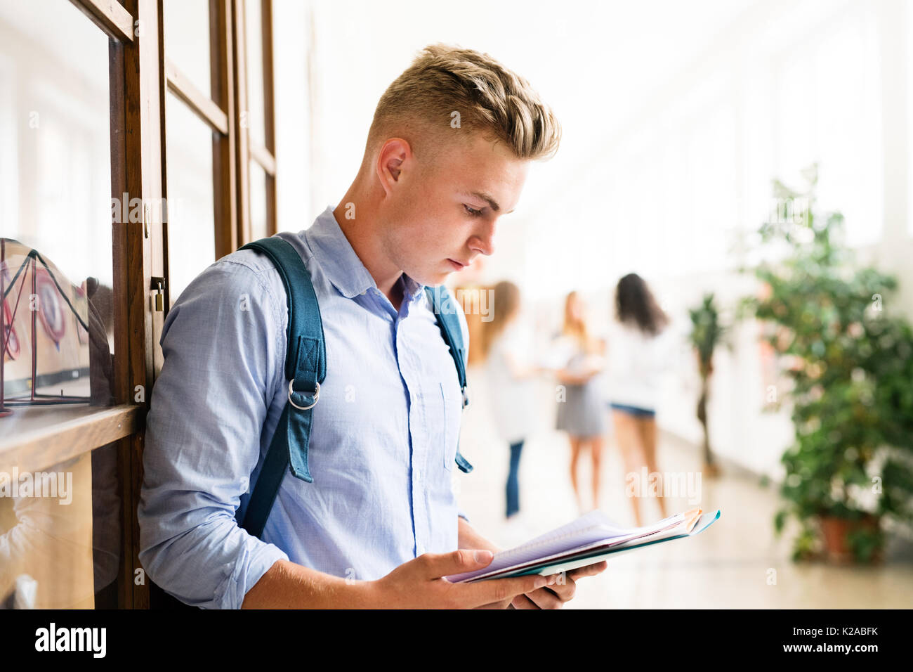 Teenage boy with notebooks in high school hall during break Stock Photo ...