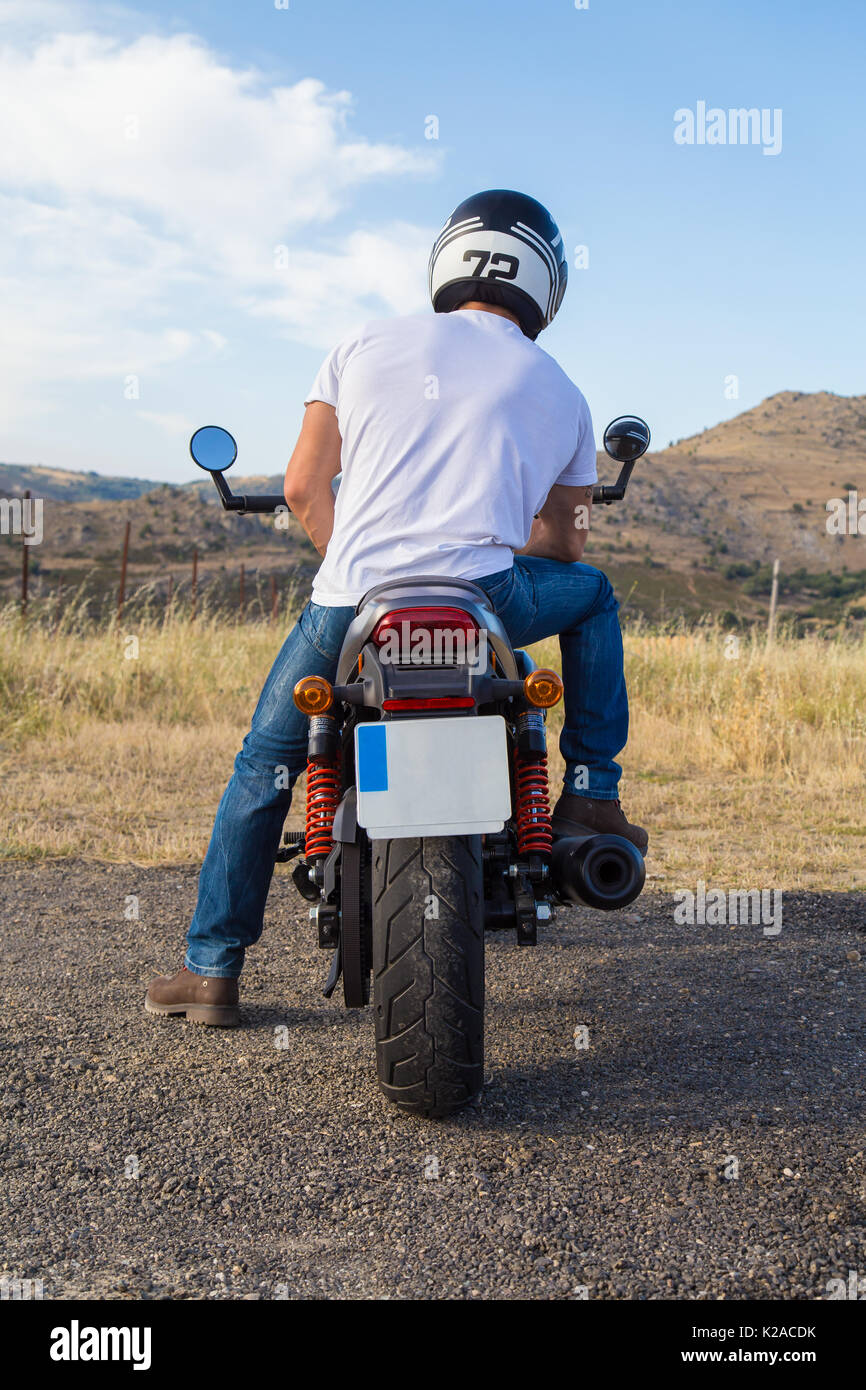 Back view of biker in helmet sitting on motorcycle in a mountain area ...