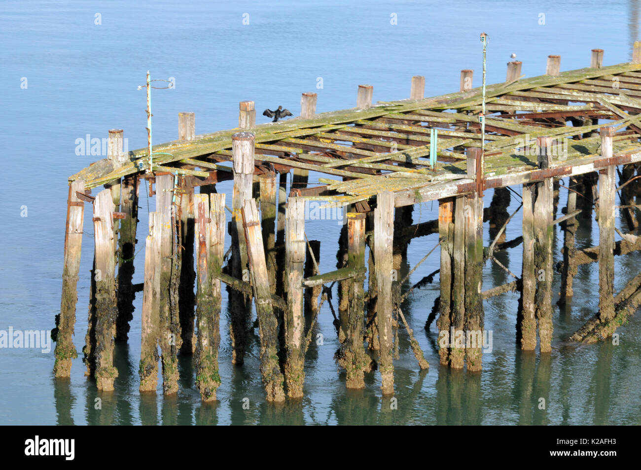 A rickety old tumbledown jetty or pier in the sea falling down derelict ...