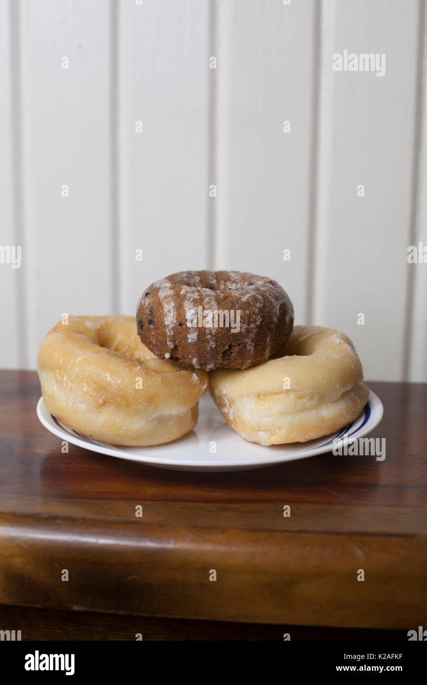 A single blueberry donut on two sweet, glazed donuts Stock Photo - Alamy
