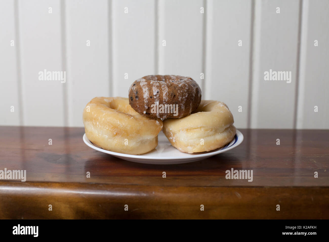 A single blueberry donut on two sweet, glazed donuts Stock Photo - Alamy