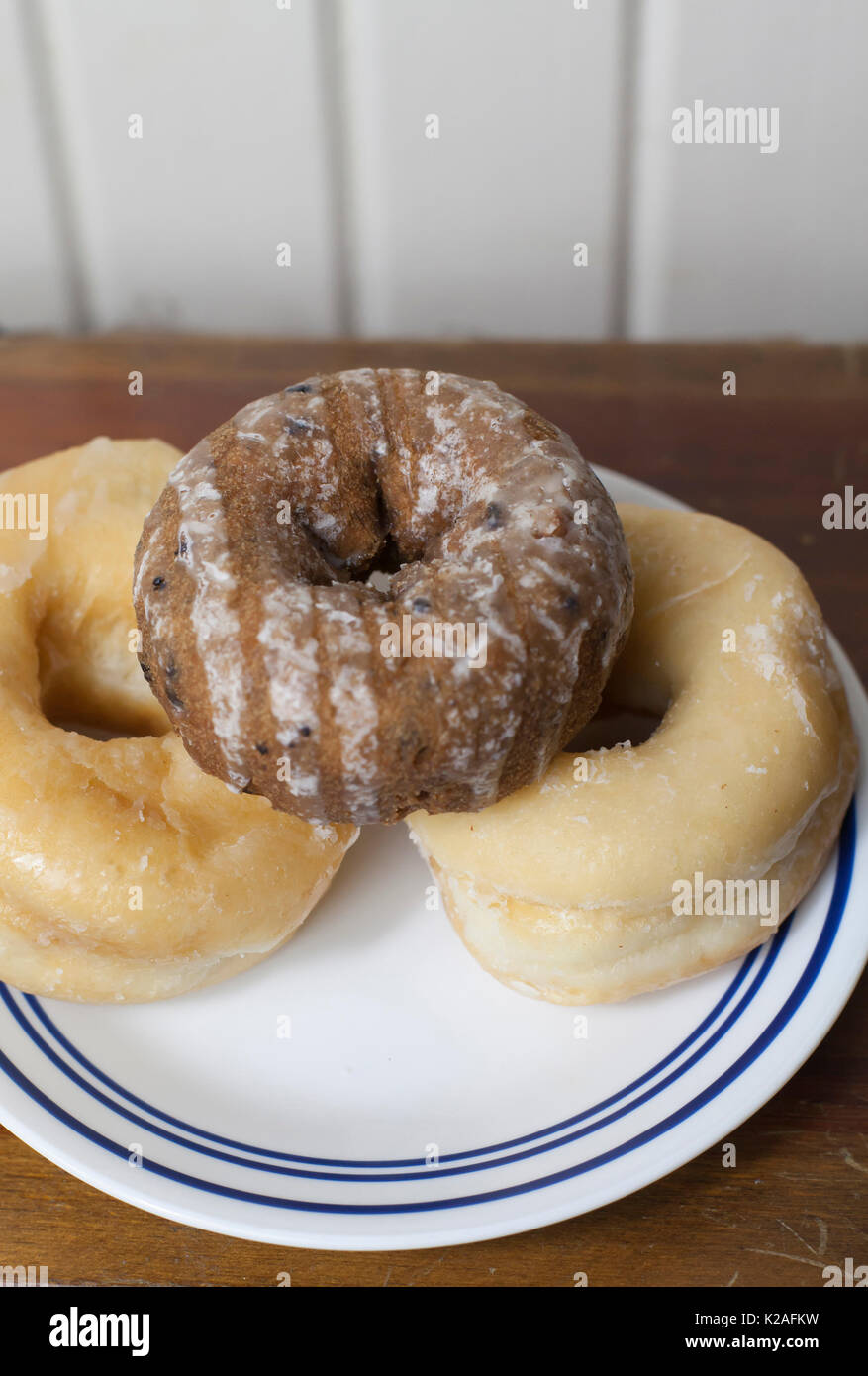 A single blueberry donut on two sweet, glazed donuts Stock Photo - Alamy