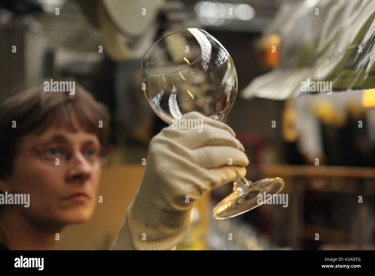 Glass factory worker checks the quality of stemware on the production ...
