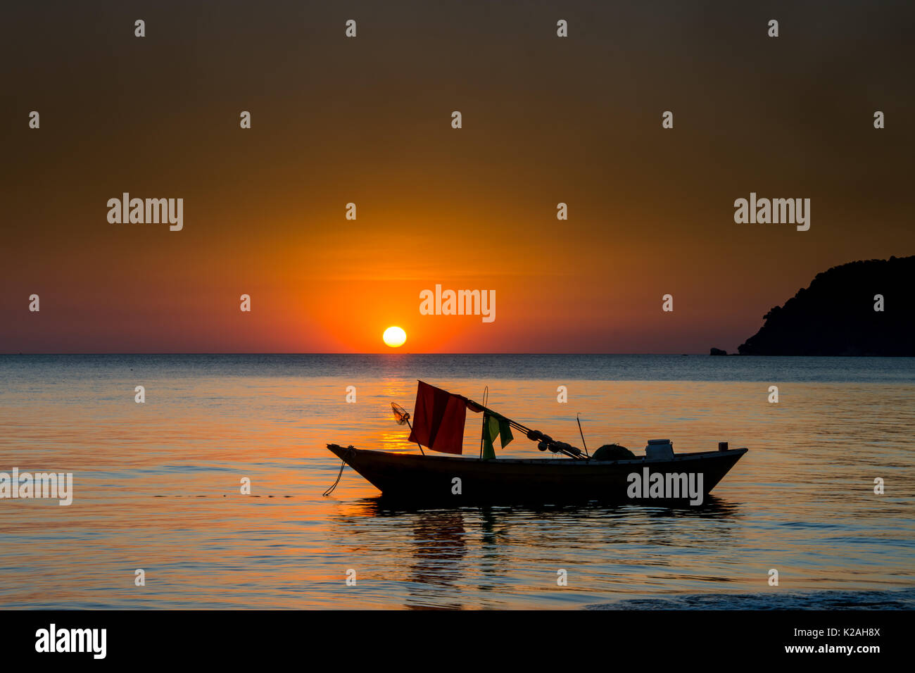 Fishing boat on sea during sunset Stock Photo - Alamy