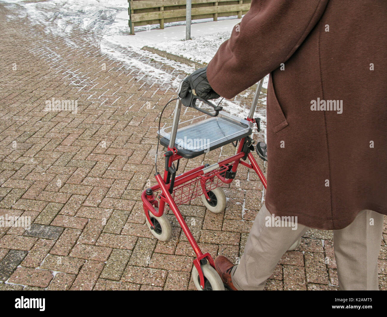 Senior male walking behind wheeled walker in snow Stock Photo - Alamy