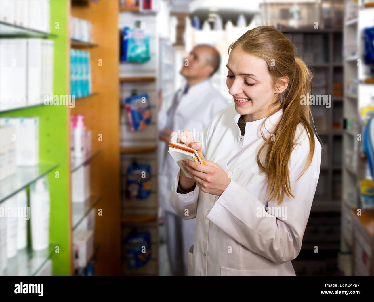 Elderly pharmacist and positive assistant working at farmacy reception ...