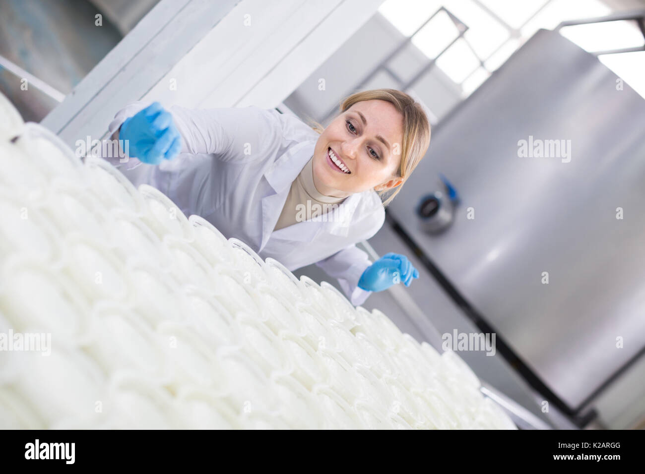 Portrait of adult woman dressed in white coat working on cottage cheese ...