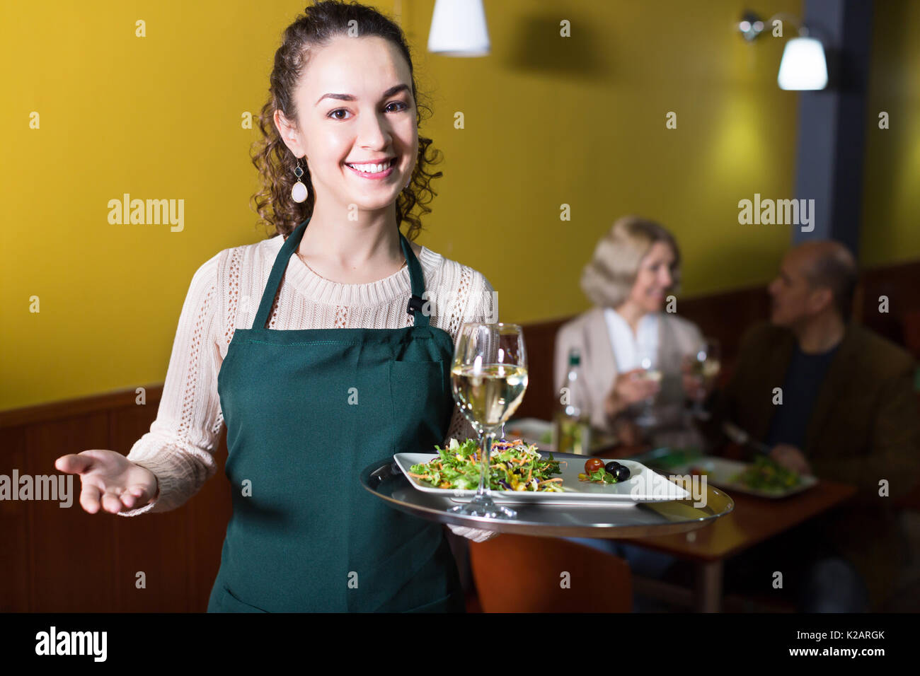 Positive young waitress greeting customers at table in restaurant Stock ...