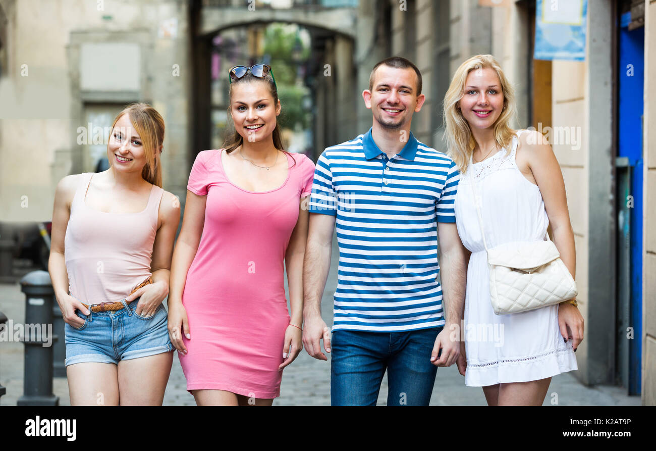 portrait of four happy young people taking walk in town together on ...