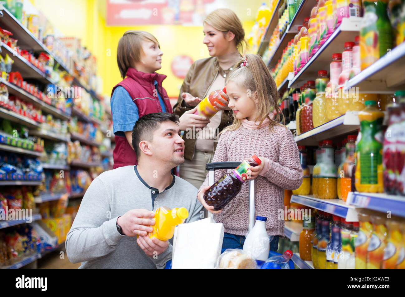 Happy young family of customers with children purchasing carbonated ...