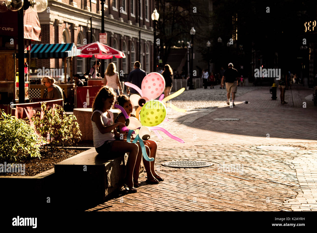 Two girls sitting with balloons Stock Photo - Alamy