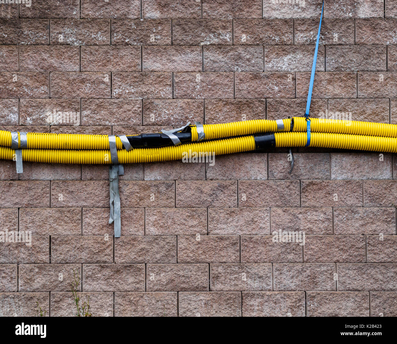Yellow drainage pipes held together with tape on a brick wall Stock ...