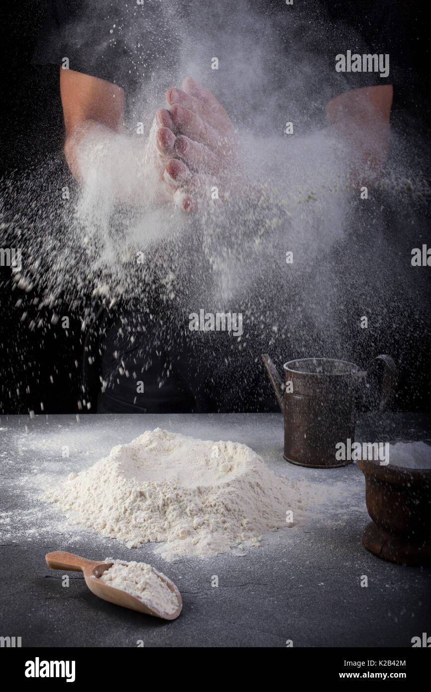 Baker clapping hands of flour on black background Stock Photo - Alamy