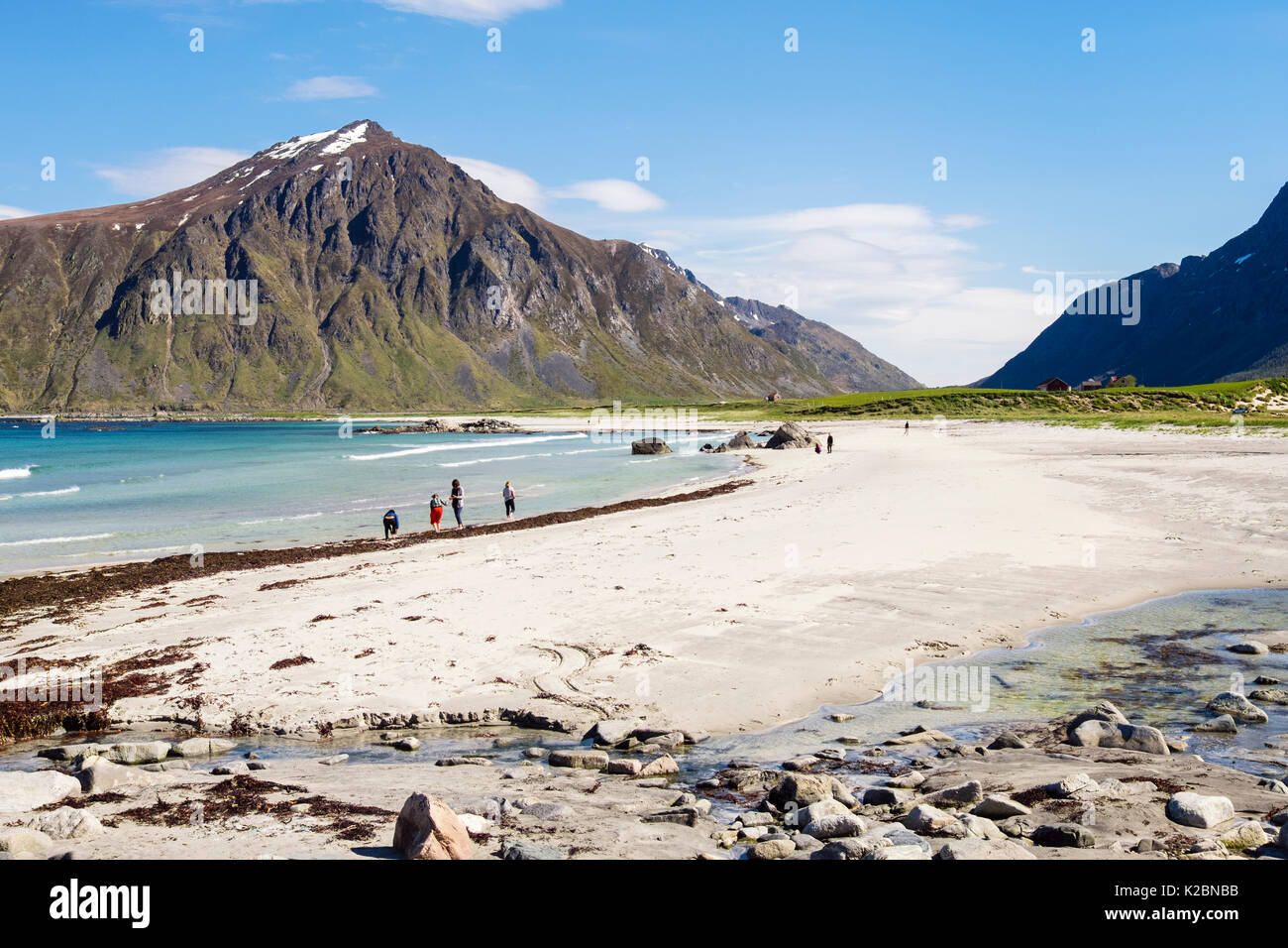 Tourists paddling on quiet sandy Skagsanden beach in summer. Flakstad ...