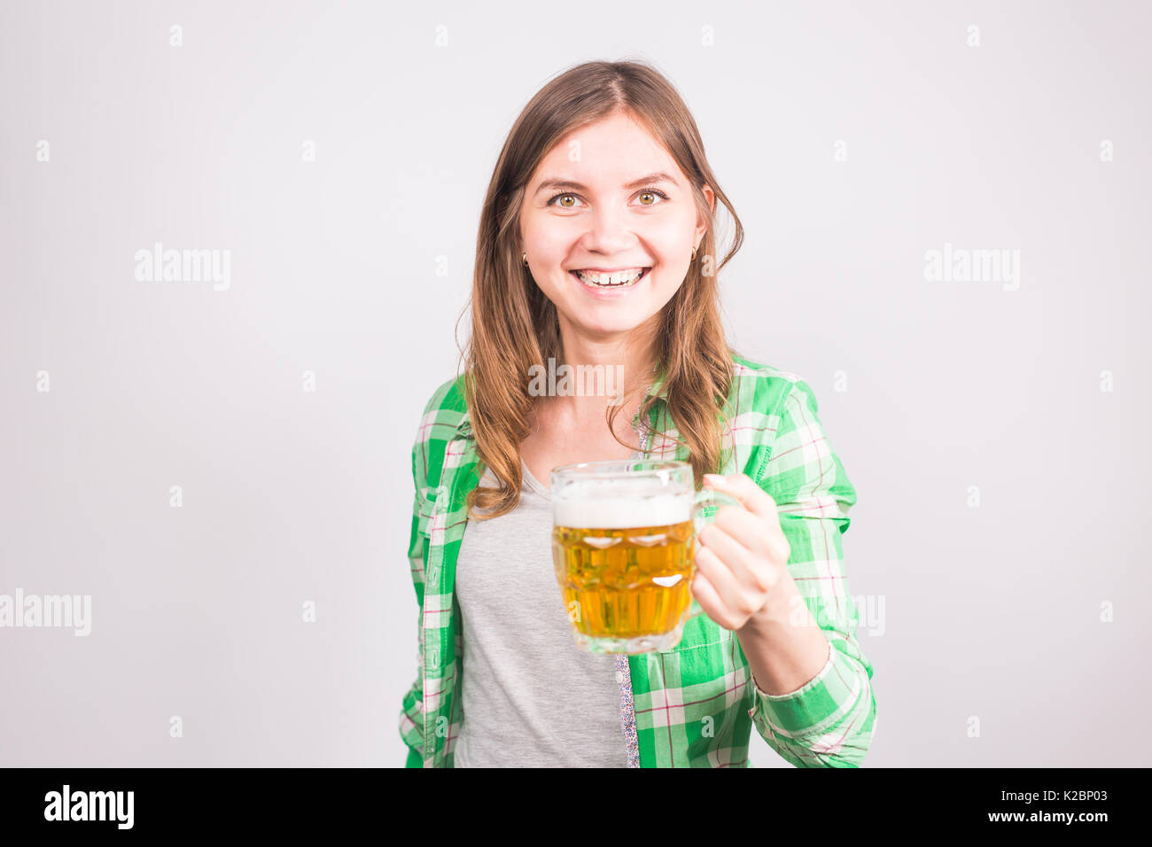Cheerful young woman holding a beer mug full of beer and smiling on ...