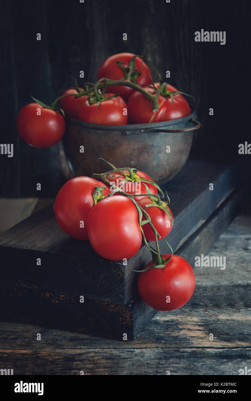 Ripe red tomatoes on a branch lying on a wooden background in rustic ...