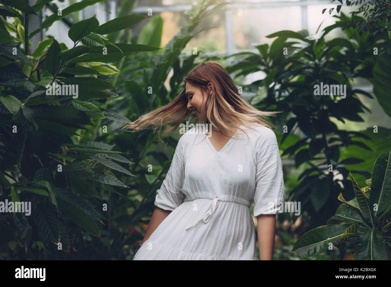 Beautiful young woman standing in tropical botanical garden. Female ...