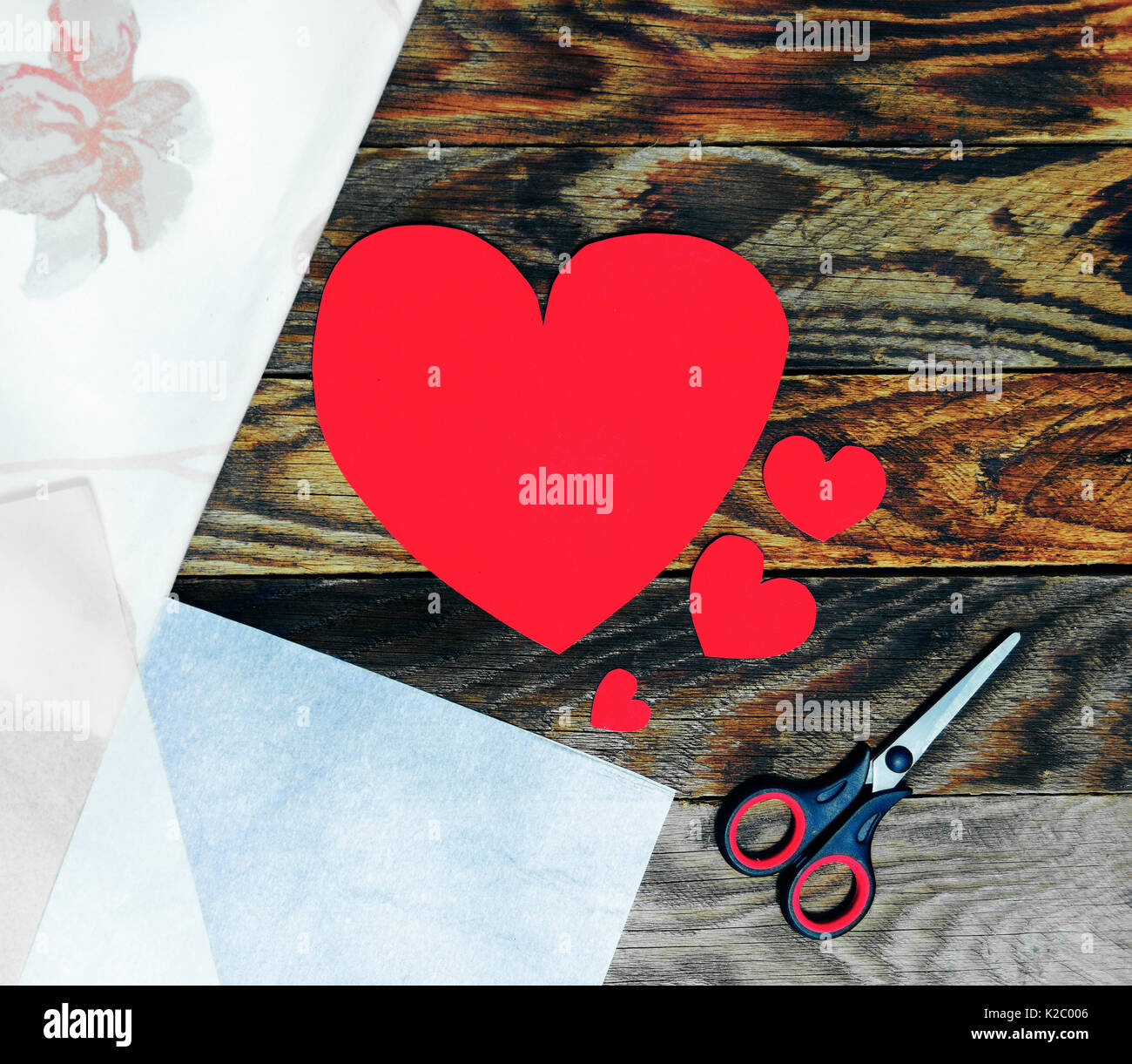 Three red hearts made of paper and scissors on the old dark wooden ...