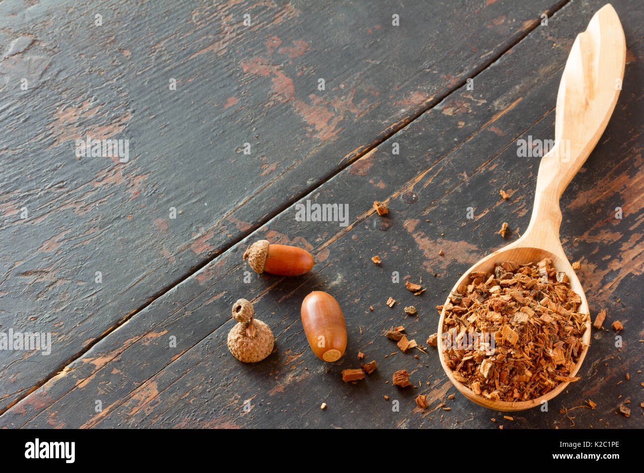 acorns and crushed oak bark in a wooden spoon on an old black wooden ...