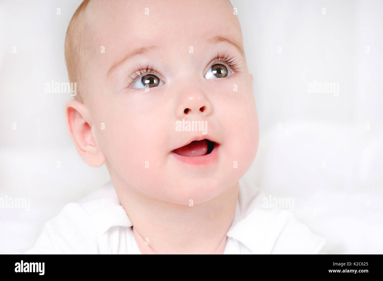 Happy smiling child with wide open brown eyes on white background ...