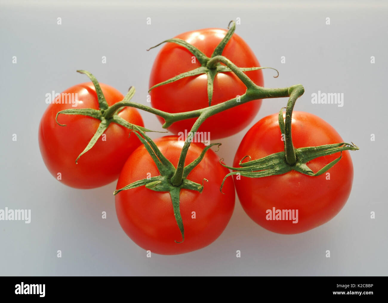 Four Red Tomatoes on the Vine Stock Photo - Alamy