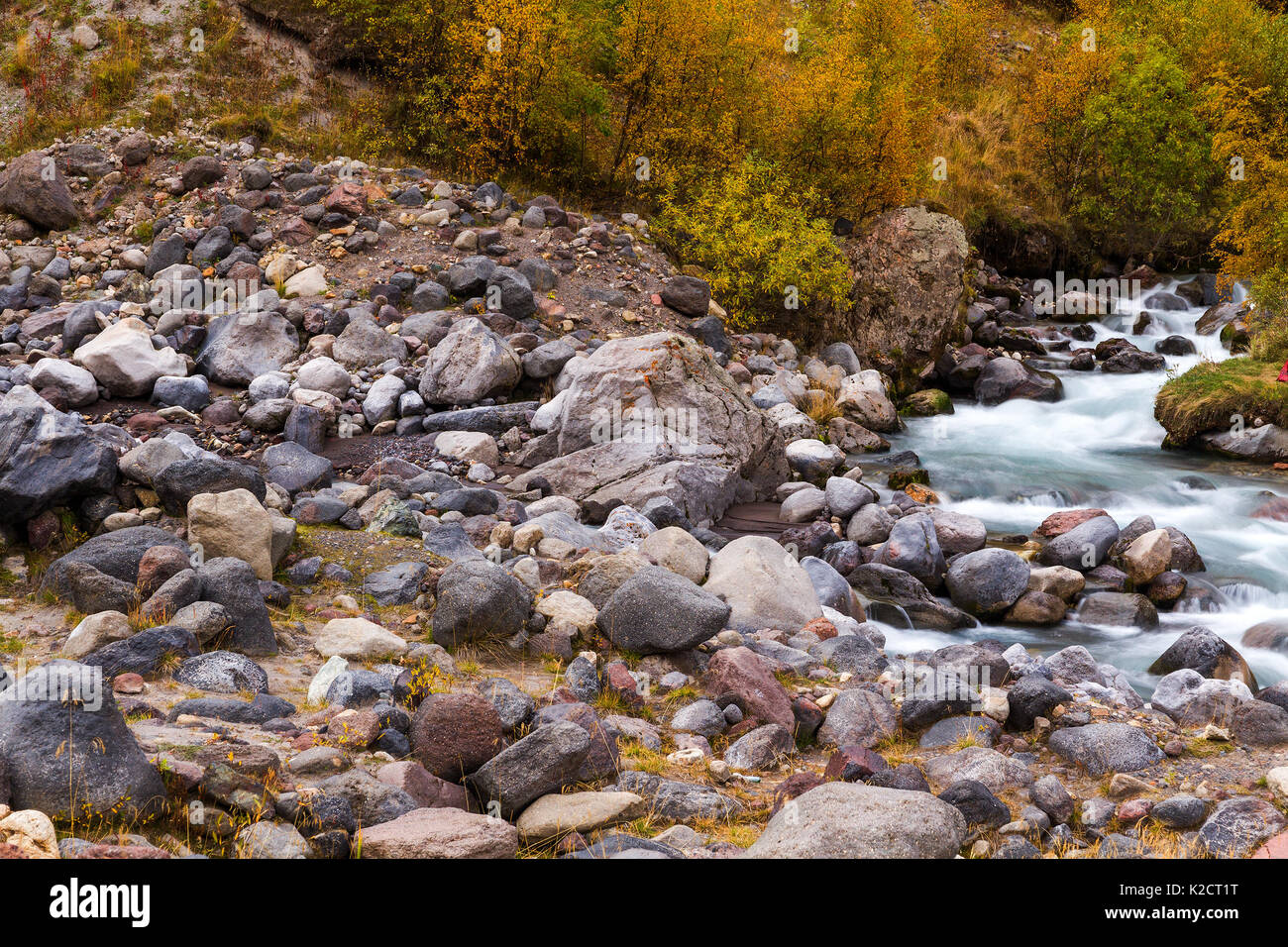 Mountain stream by an autumn surrounded by trees with yellow foliage ...