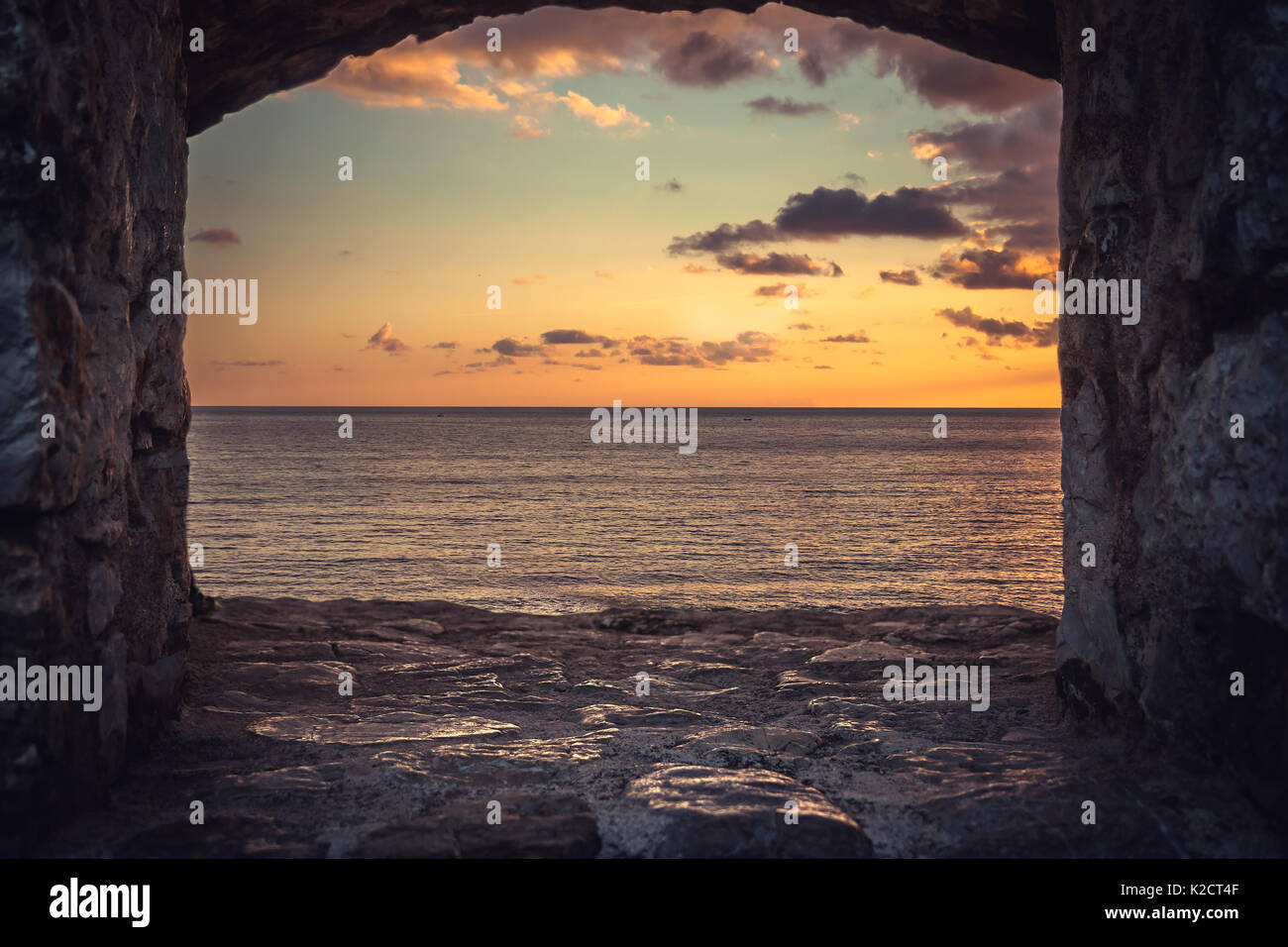 View of beautiful sunset over sea through window of old building with ...