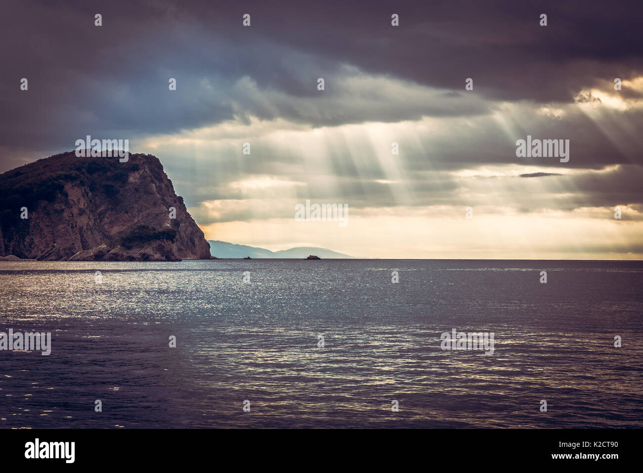 Scenic landscape with cliff rock at sea during sunset with sun rays ...