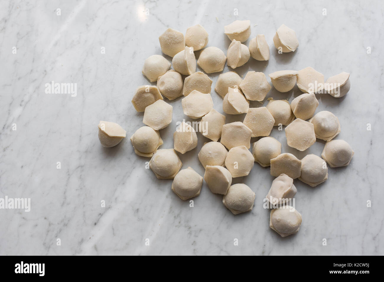 Raw frozen pastry dumplings close up over white rustic stone background ...
