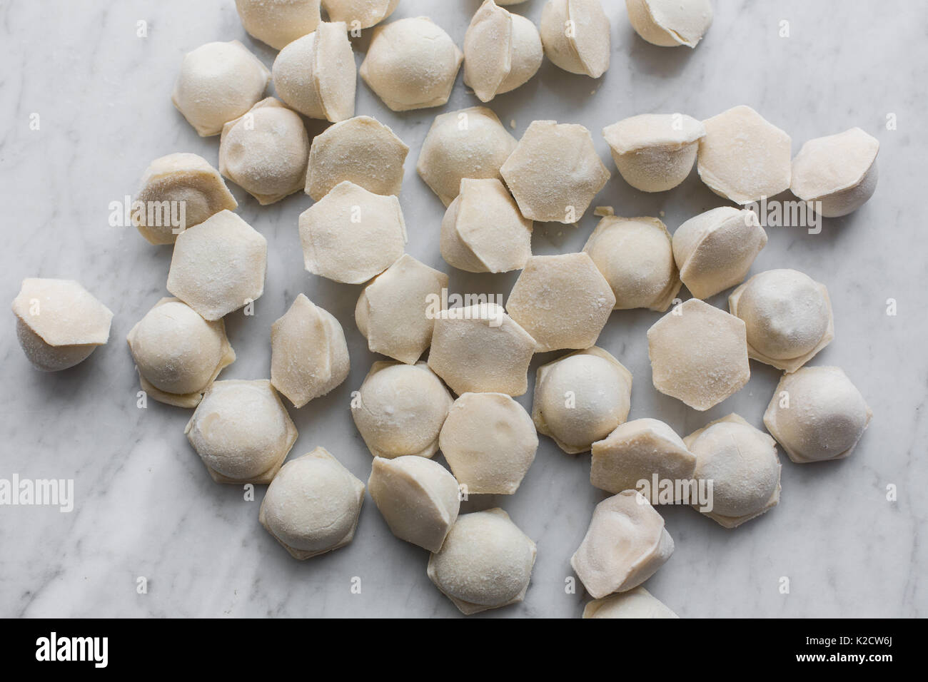 Raw frozen pastry dumplings close up over white rustic stone background ...