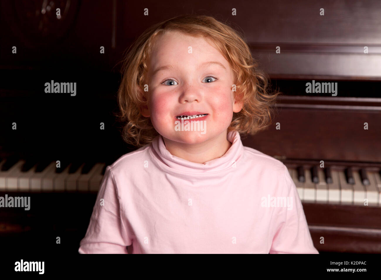 a cute curly red haired child gives a big toothy grin at home on the ...