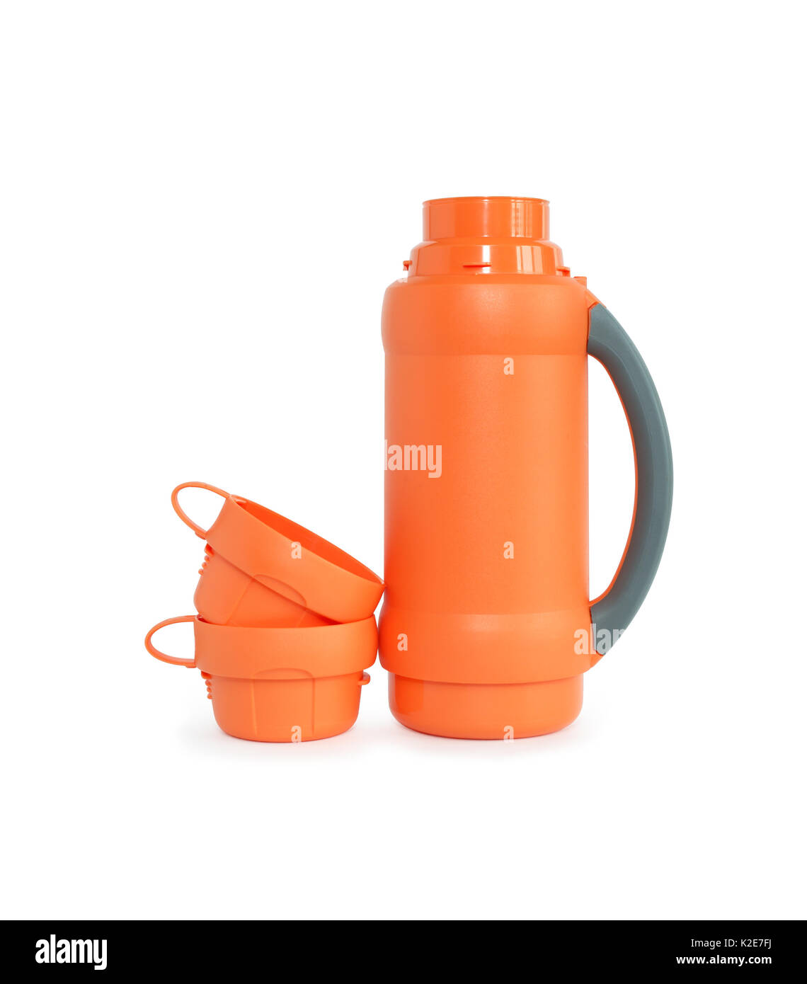 Open modern orange thermos standing near mugs on white background ...