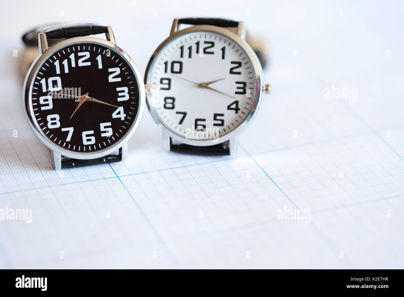 Pair of modern wristwatches standing on graph paper surface Stock Photo ...