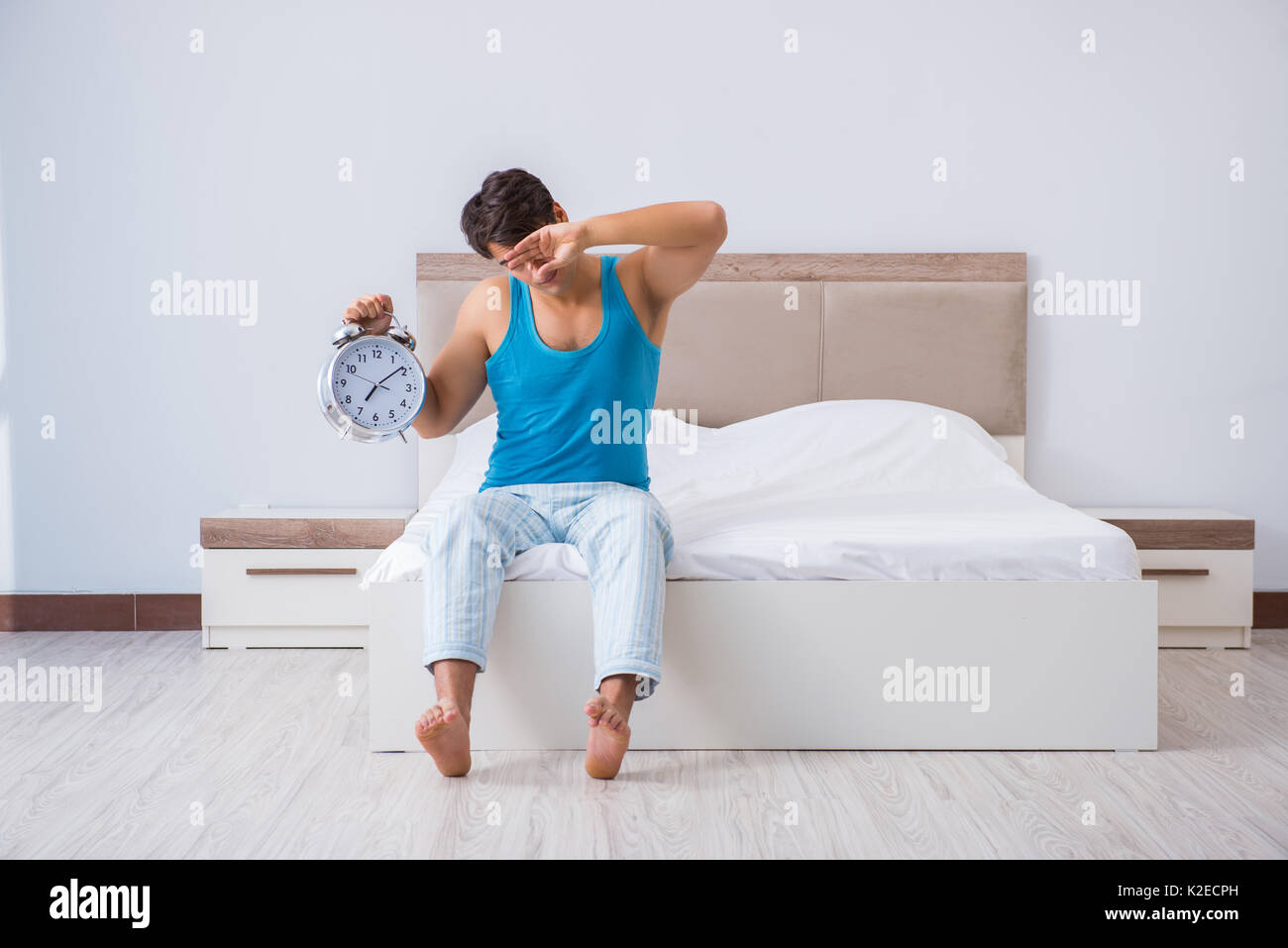 Young man waking up in bed Stock Photo - Alamy