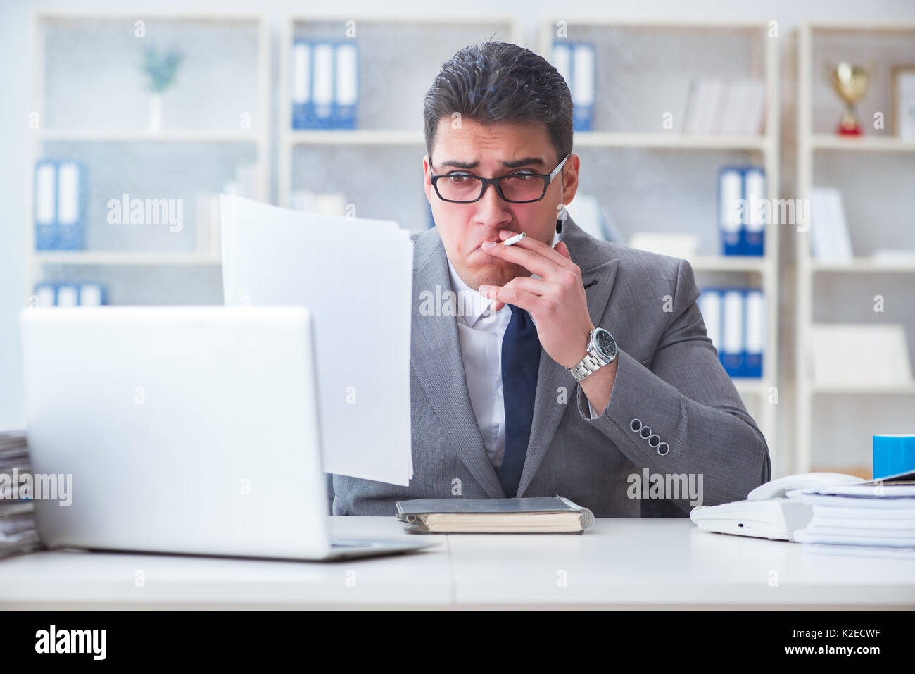 Businessman smoking in office at work Stock Photo - Alamy