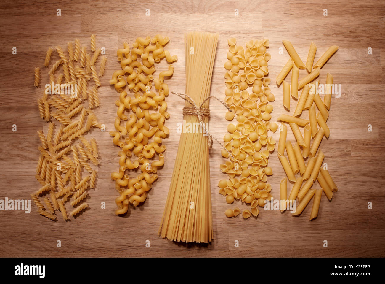 Close up of several types of dry pasta on light wooden table, top view ...
