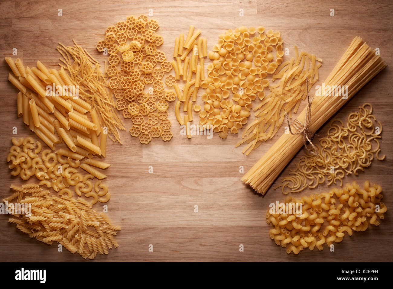 Close up of several types of dry pasta on light wooden table, top view ...