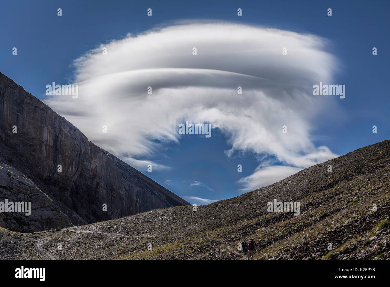 Hikers on trail in the Ubaye valley with Lenticular cloud formation ...