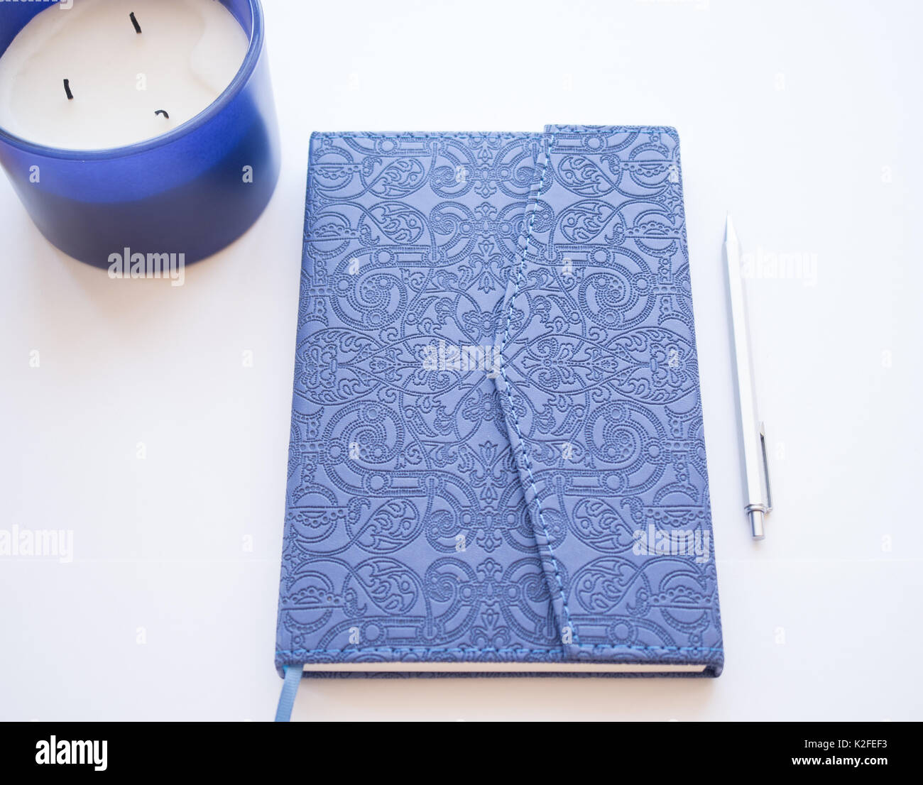 Concept photo on a white background with blue diary, pen and candle ...