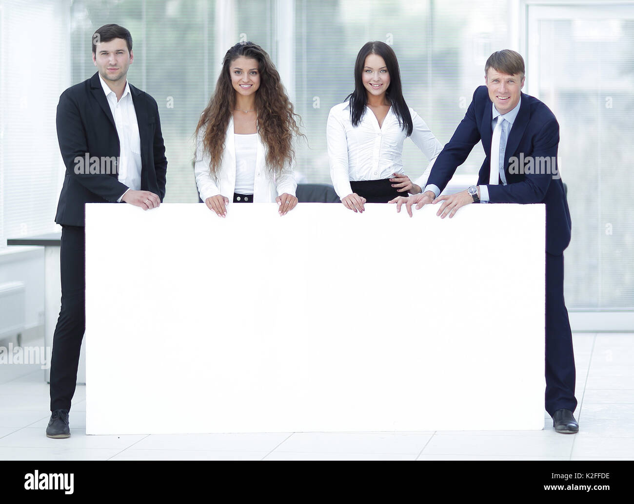 business team holding blank white banner Stock Photo - Alamy