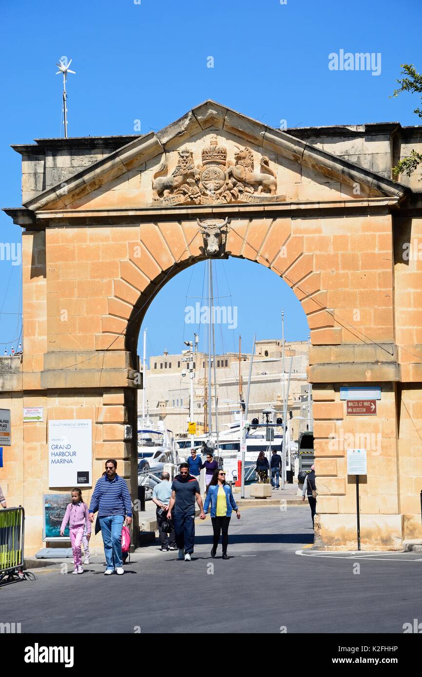 Tourists walking through an arch leading to the Grand Harbour marina ...