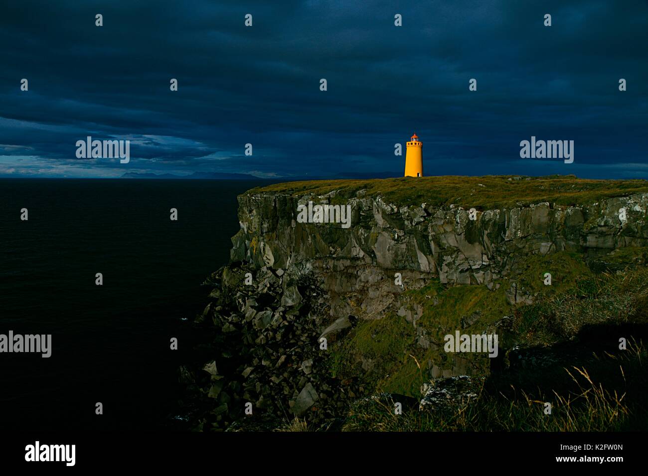 A lighthouse, built on a cliff in Iceland, reflects the last fading ...